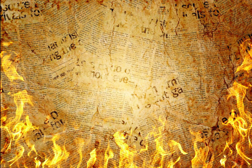 Burning newspapers with flame background - The Corvallis Advocate